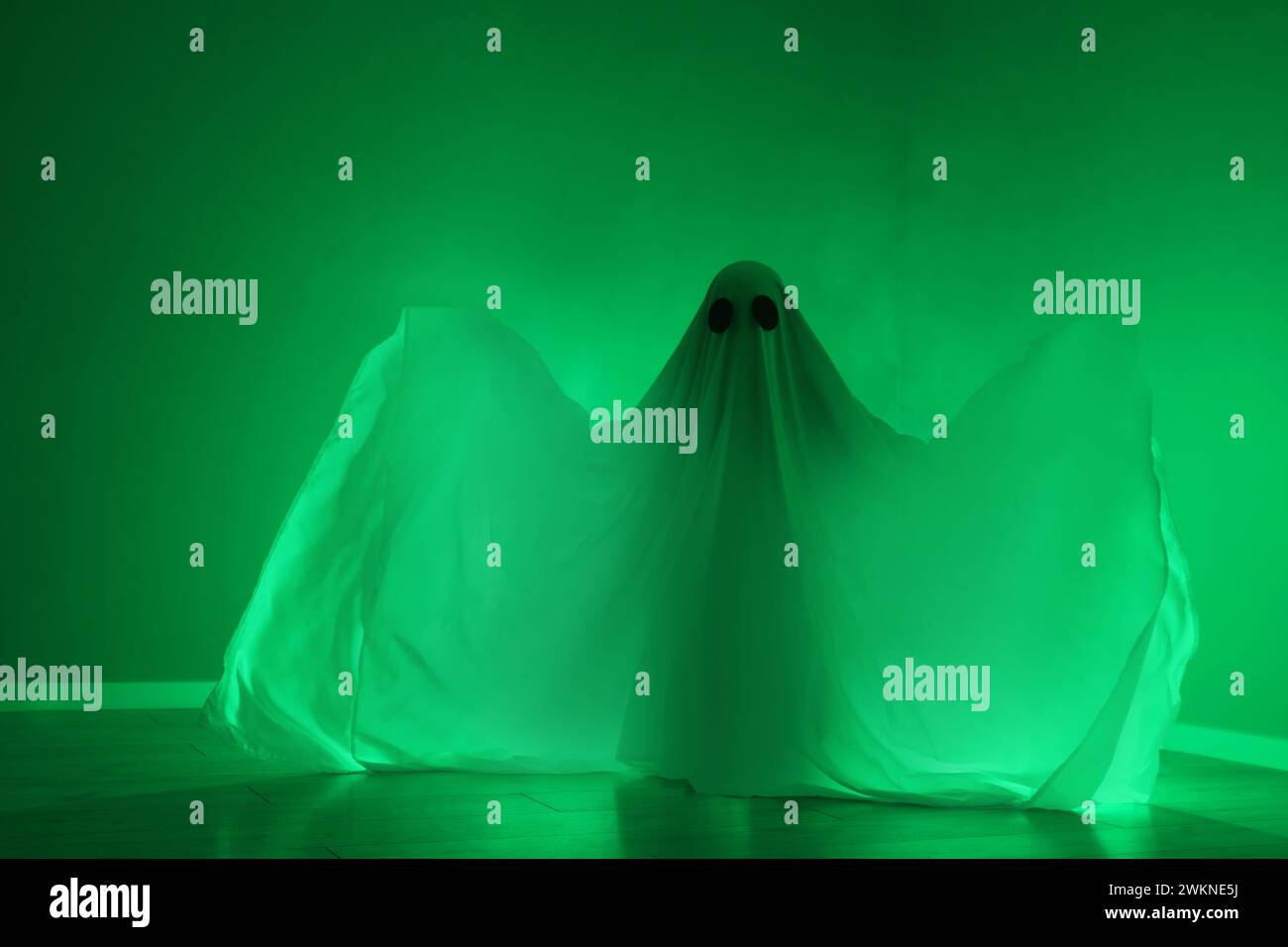 Creepy ghost. Woman covered with sheet in green light Stock Photo - Alamy