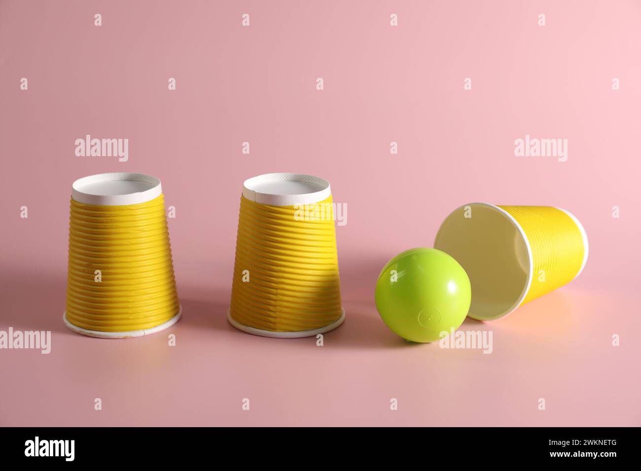 Shell game. Three yellow cups and ball on pink background Stock Photo ...