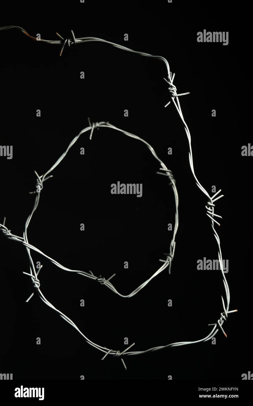 Shiny metal barbed wire on black background Stock Photo - Alamy