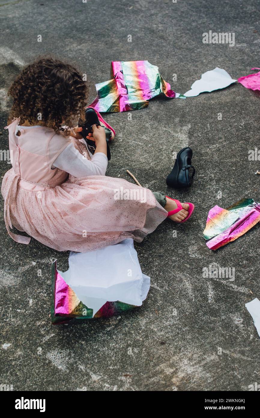 little girl opening birthday present, shoes with ripped wrapping paper ...