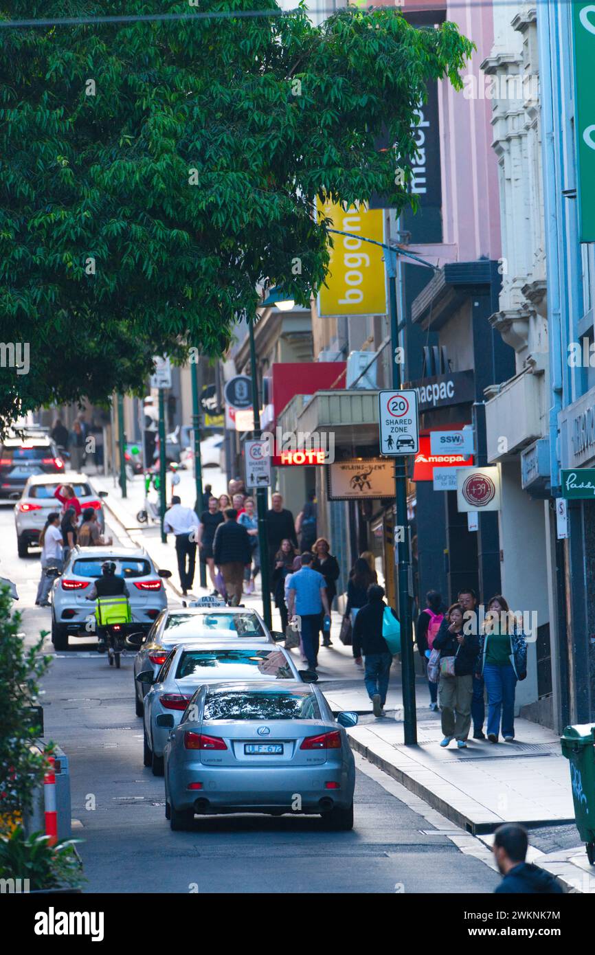 Busy city street with trees, people, cars, and pavement showing ...