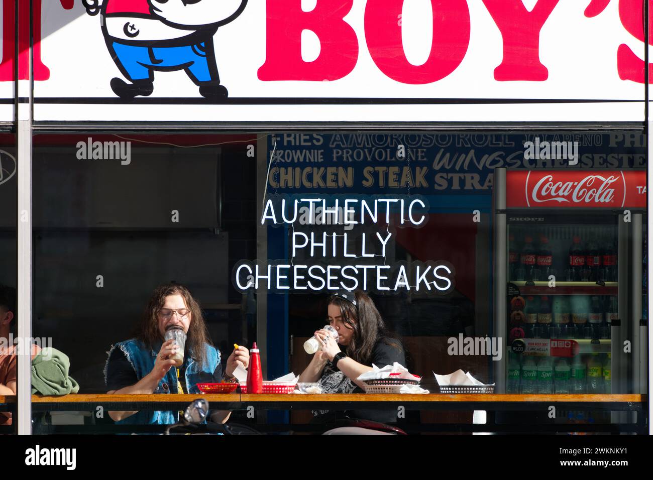 Two people eating and drinking at a cafe that offers authentic Philly ...