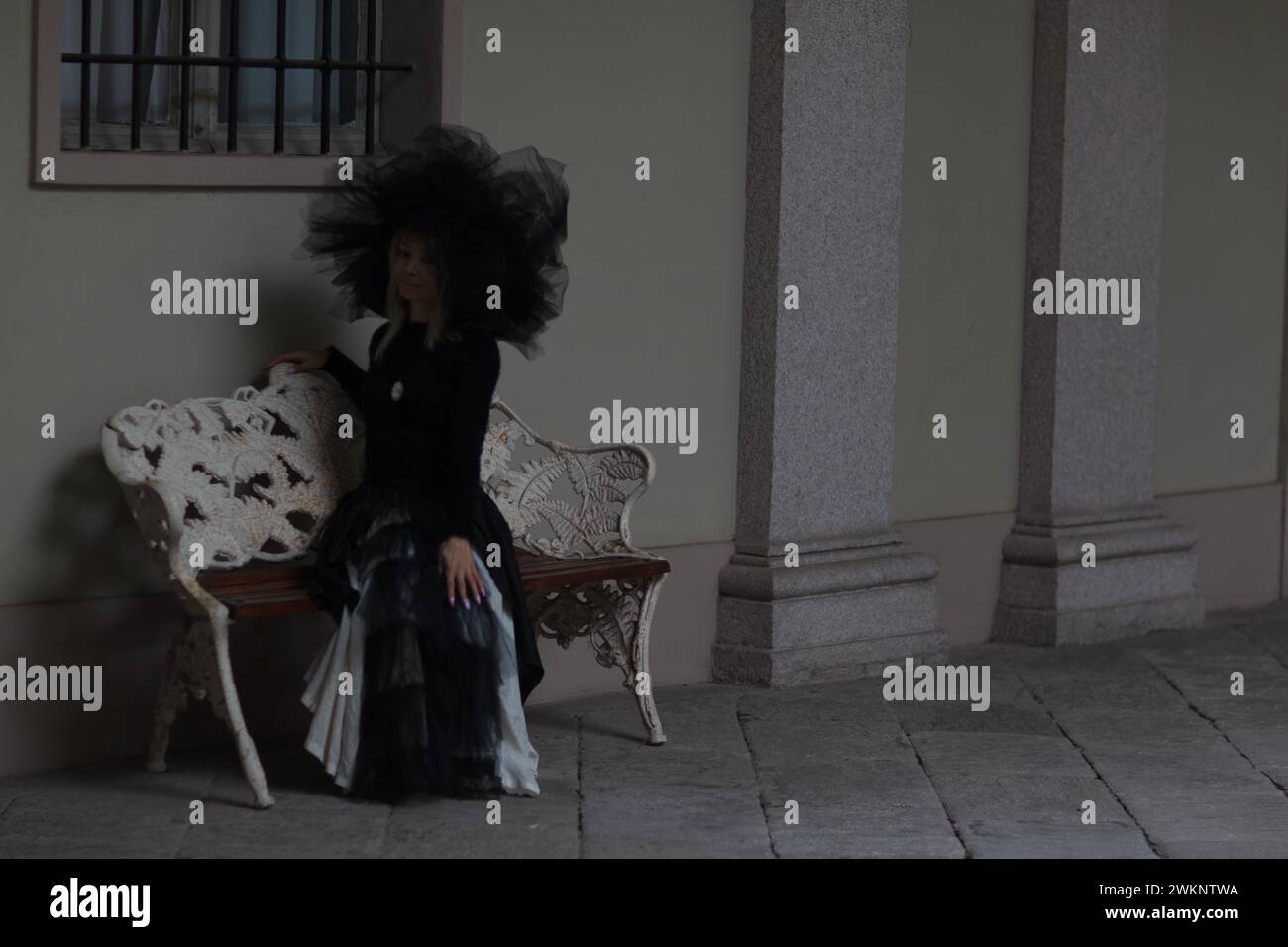 Thoughtful woman in black gothic attire sitting on a bench by a ...