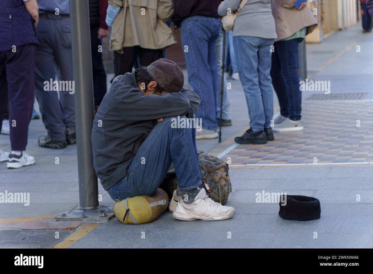 Homeless man on the street begging for alms with a sad expression, his ...