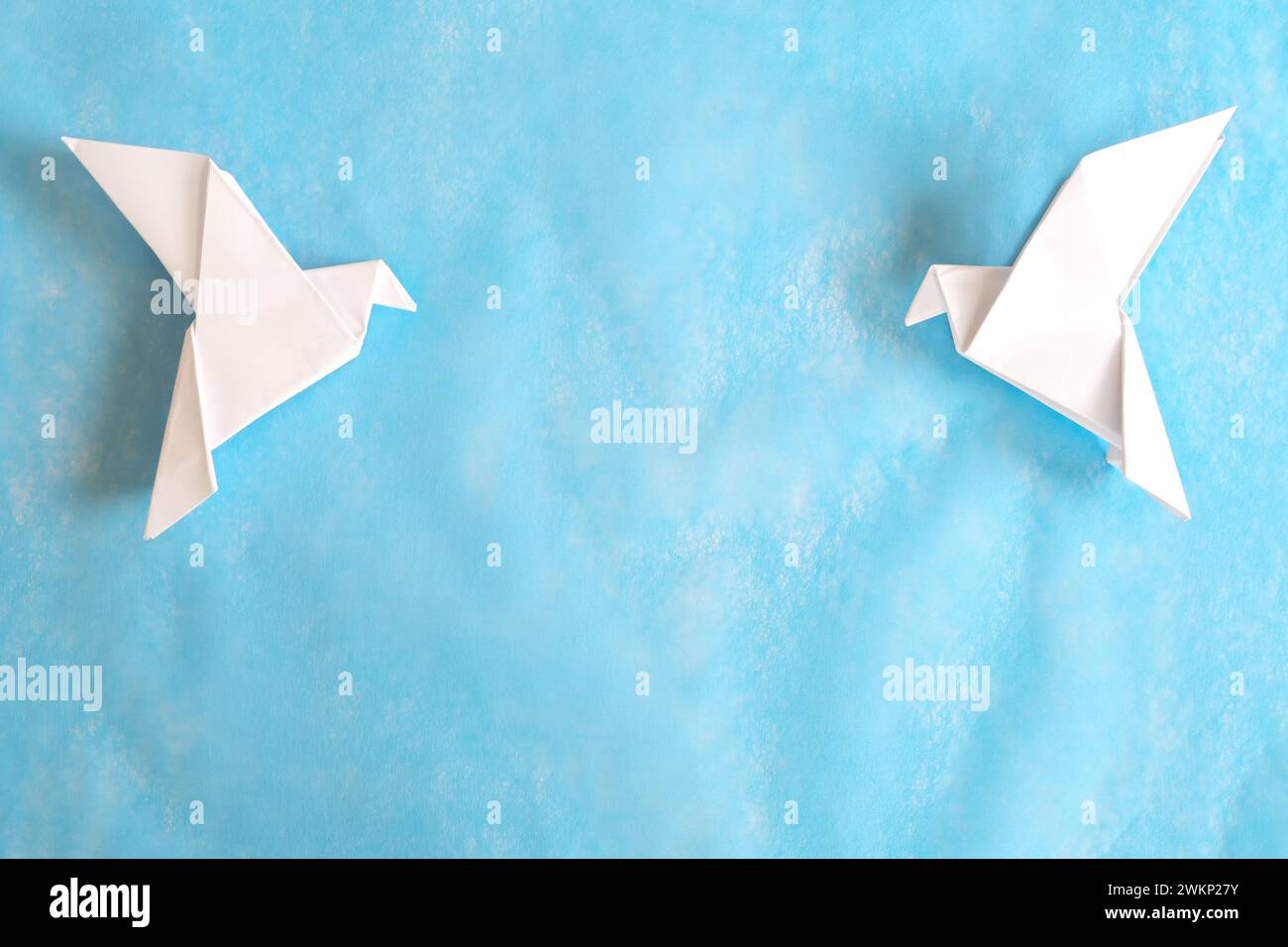 Two white dove paper cutout in blue background template with copy space ...