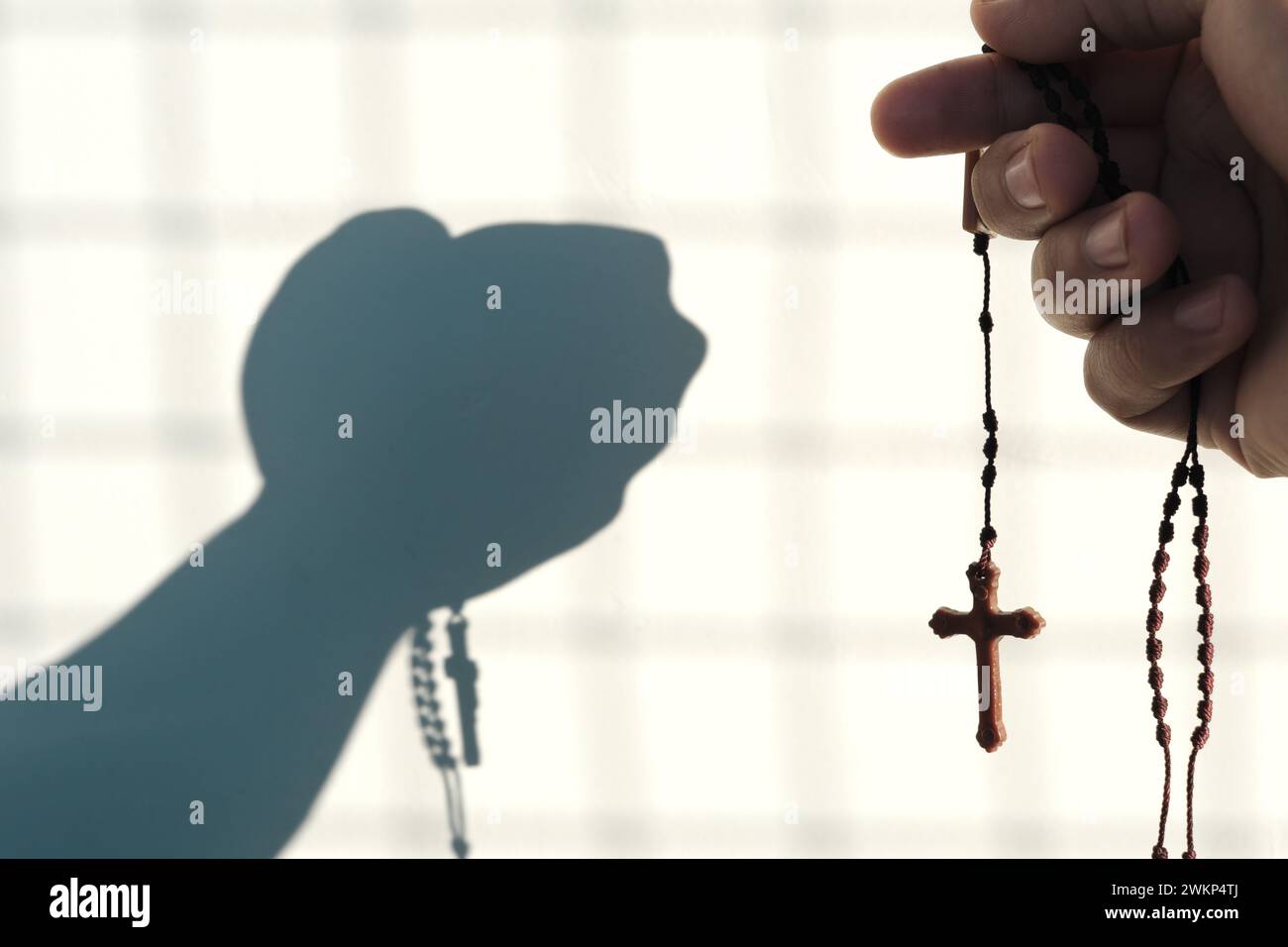 Male hand holding holy rosary with shadow. Christianity, faith and ...