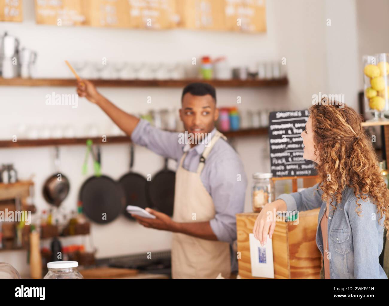 Woman, cafe and barista with pointing at menu for customer, purchase ...