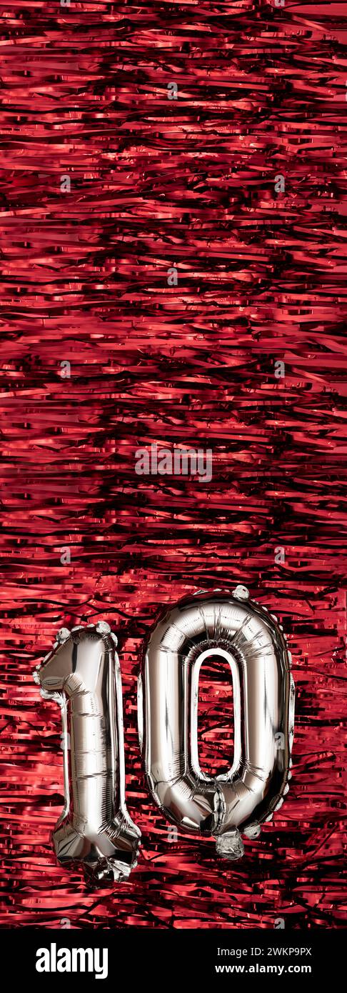 Silver foil balloon number number 10 on a background of red tinsel ...
