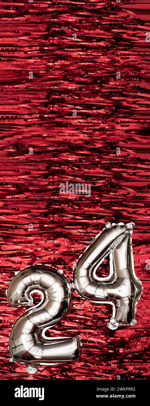 Silver foil balloon number number 24 on a background of red tinsel ...