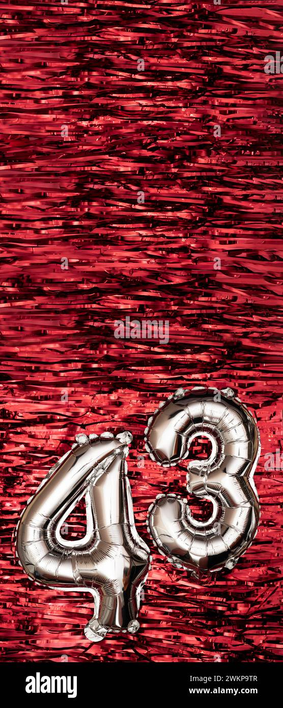 Silver foil balloon number number 43 on a background of red tinsel ...