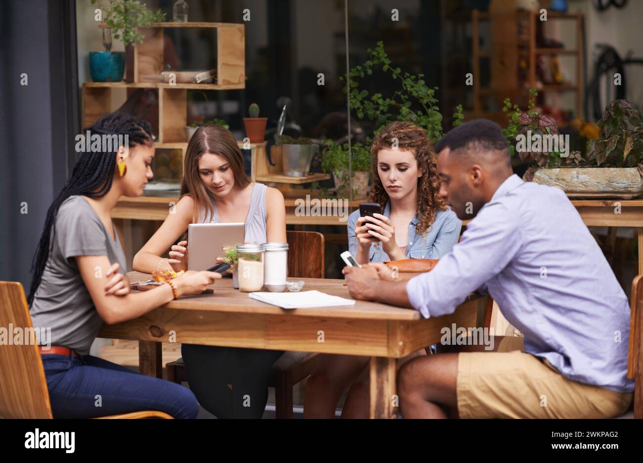 Technology, diversity and friends in restaurant together for social gathering with phone, tablet ...