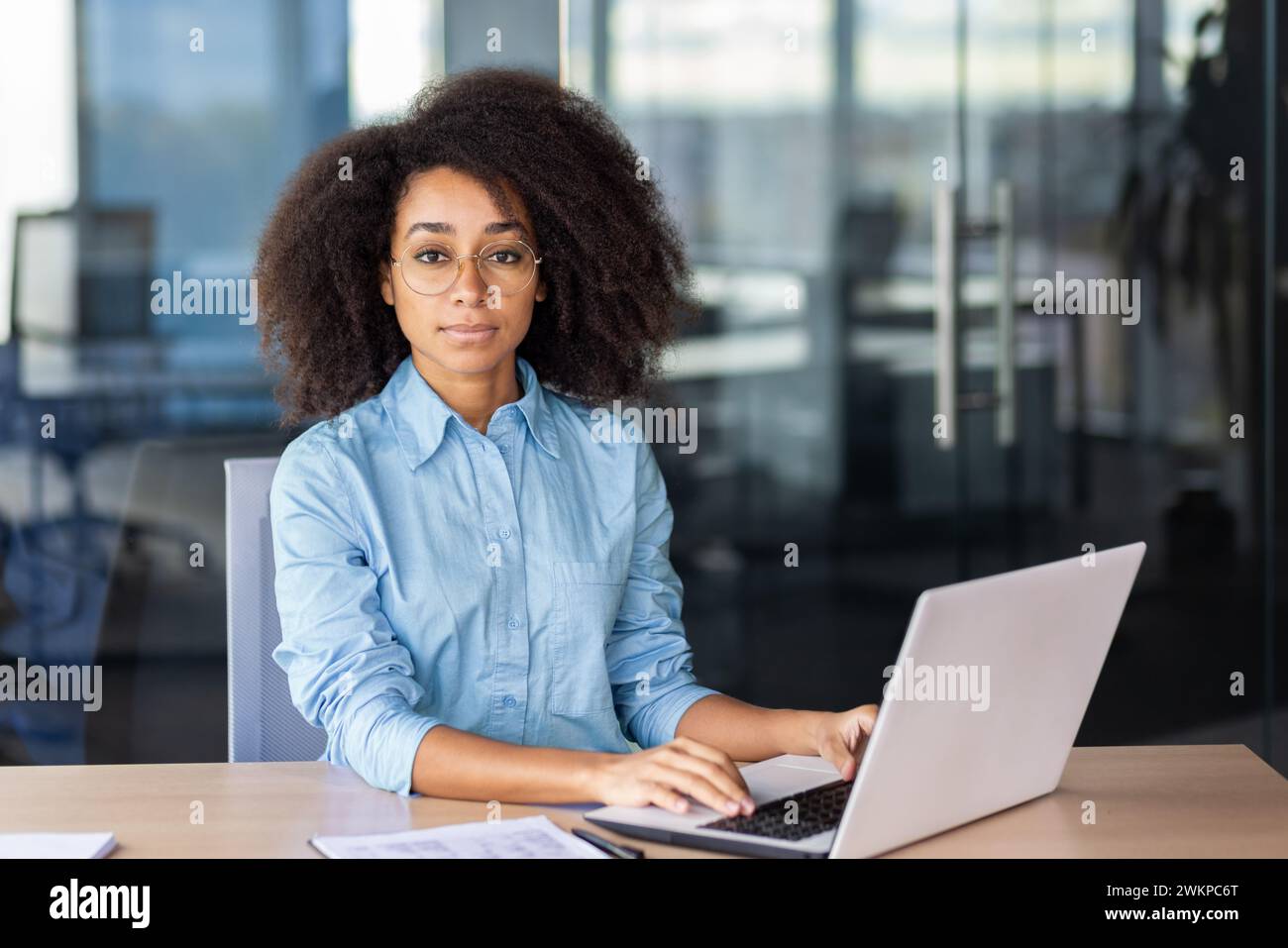 Calm hispanic lady in formal clothes sitting on chair and working by ...