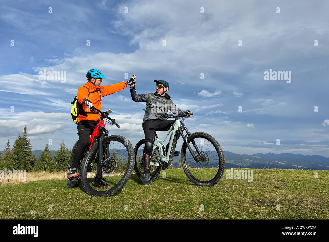 Two cyclists men riding electric bikes outdoors. Male tourists resting ...
