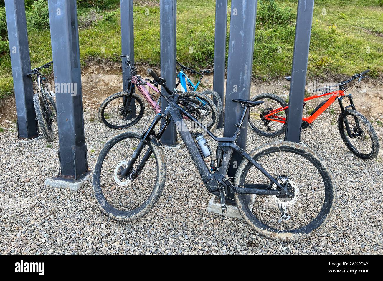 Collection of mountain electric bikes parked on a gravel-covered ground ...
