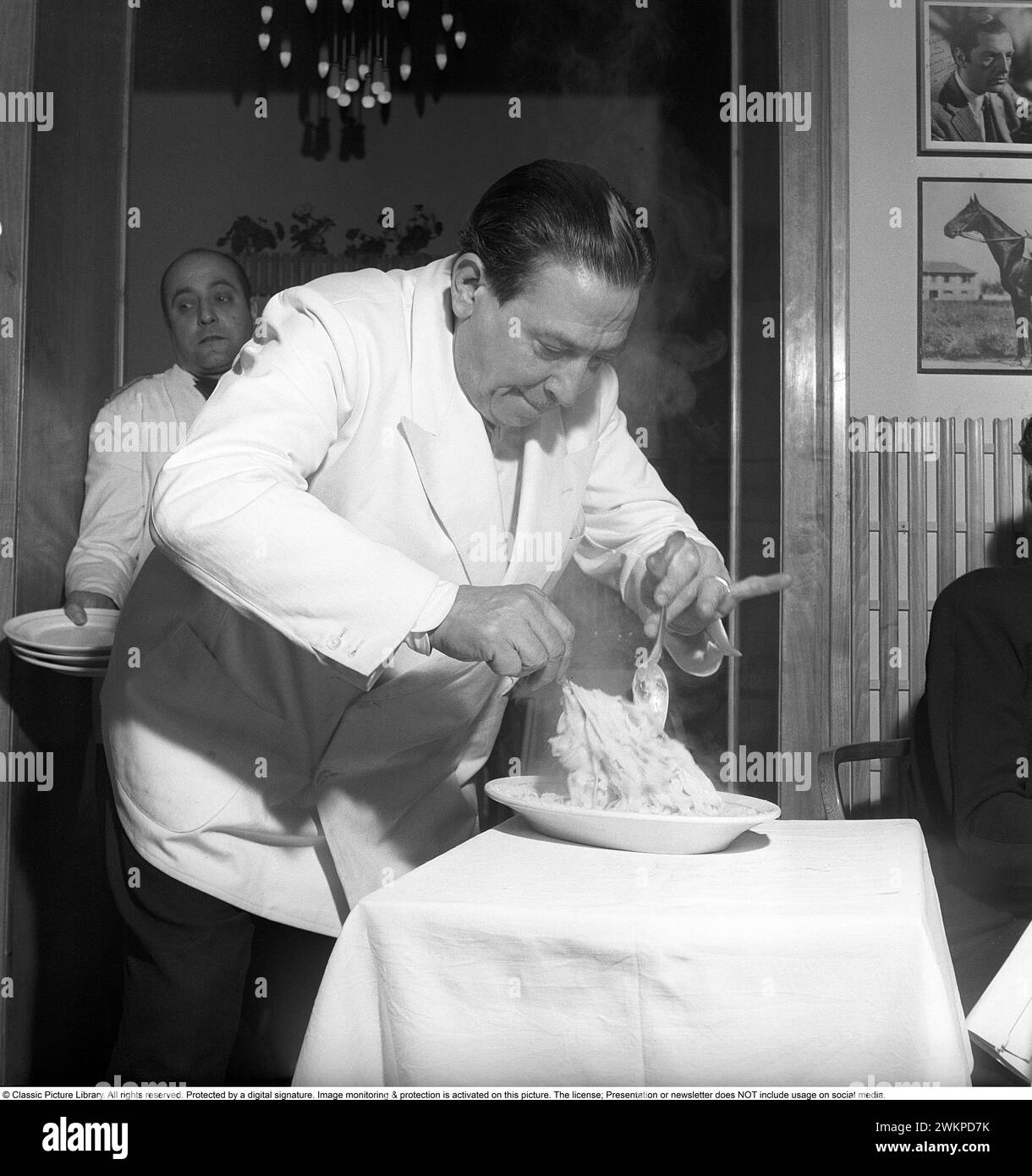 In Italy in the 1950s. A waiter at a table holds the newly cooked pasta ...