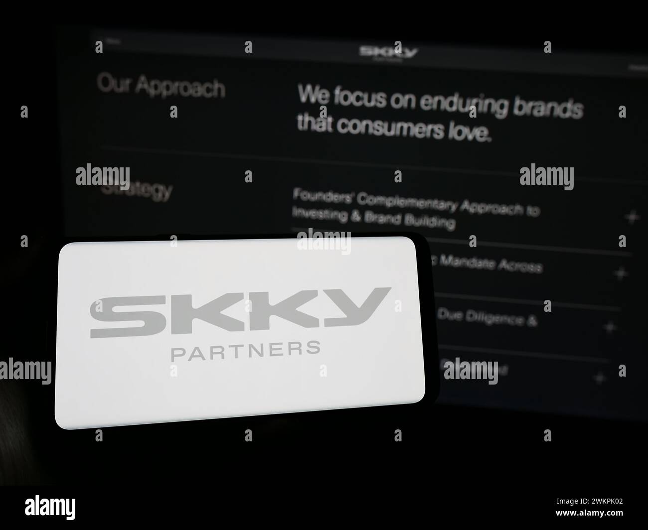 Person holding mobile phone with logo of American investment company ...