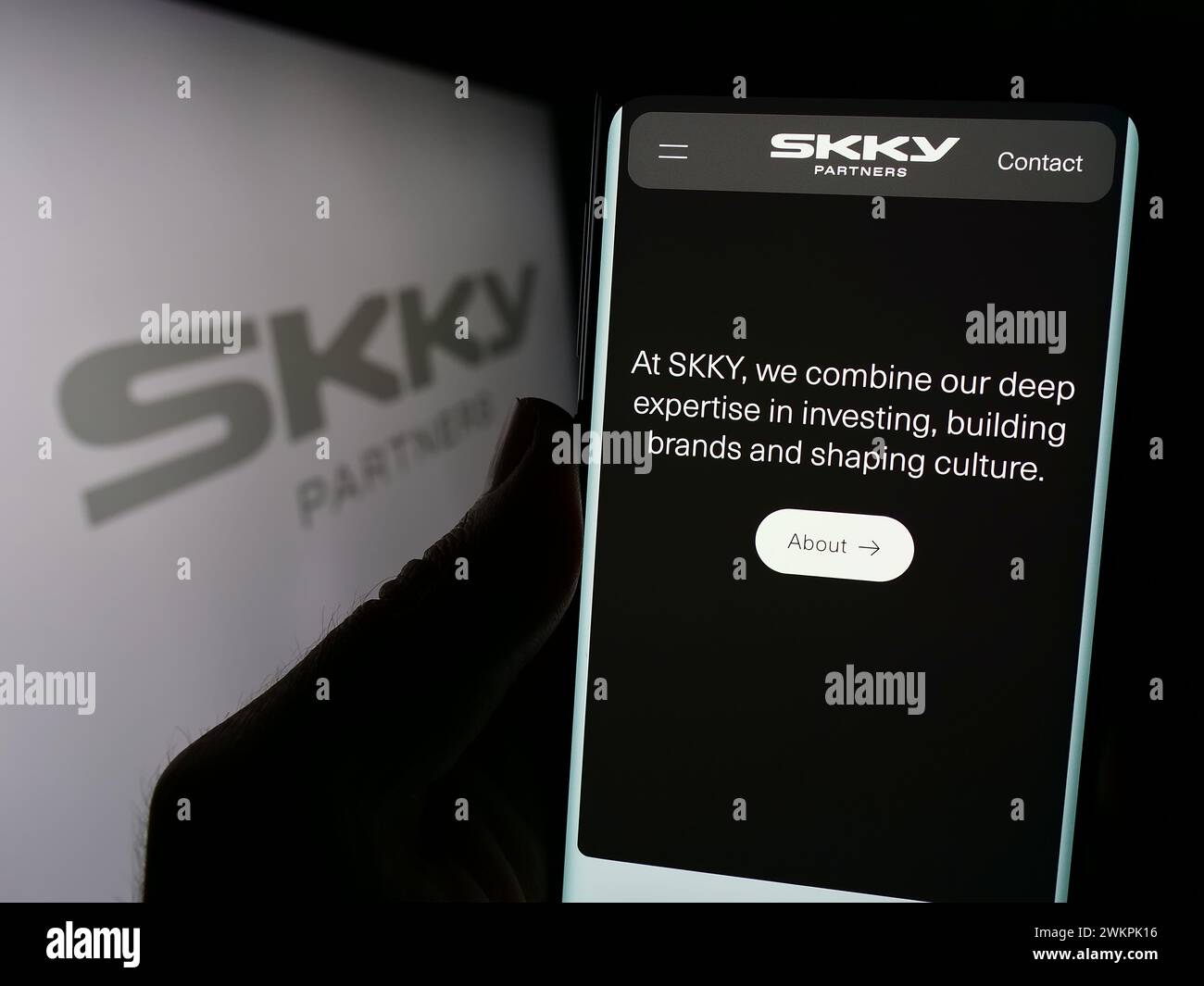 Person holding cellphone with webpage of US investment company SKKY ...