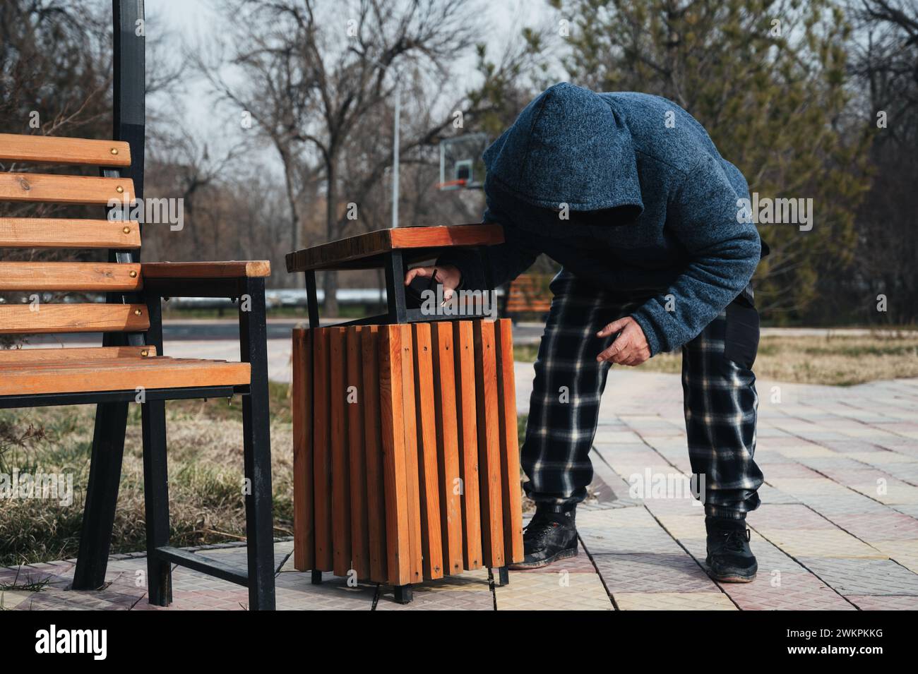 homeless elderly old Caucasian man rummages for food and garbage in a ...