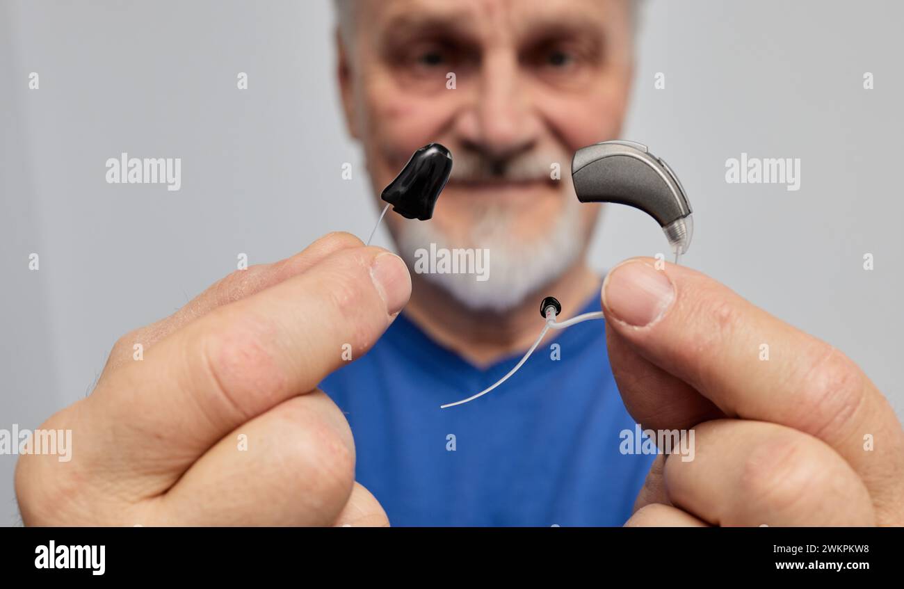 Senior man with hearing problems chooses between behind-the-ear hearing ...