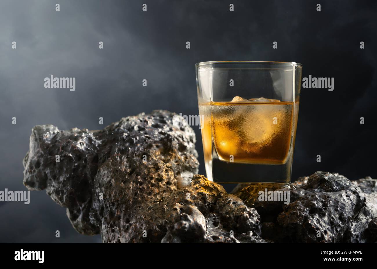 Whiskey with ice on a grey stone. Cold drink on a background of cloudy ...