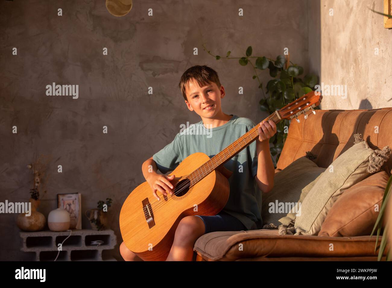 Preteen child, boy, learning how to play acoustic guitar at home, sunny ...