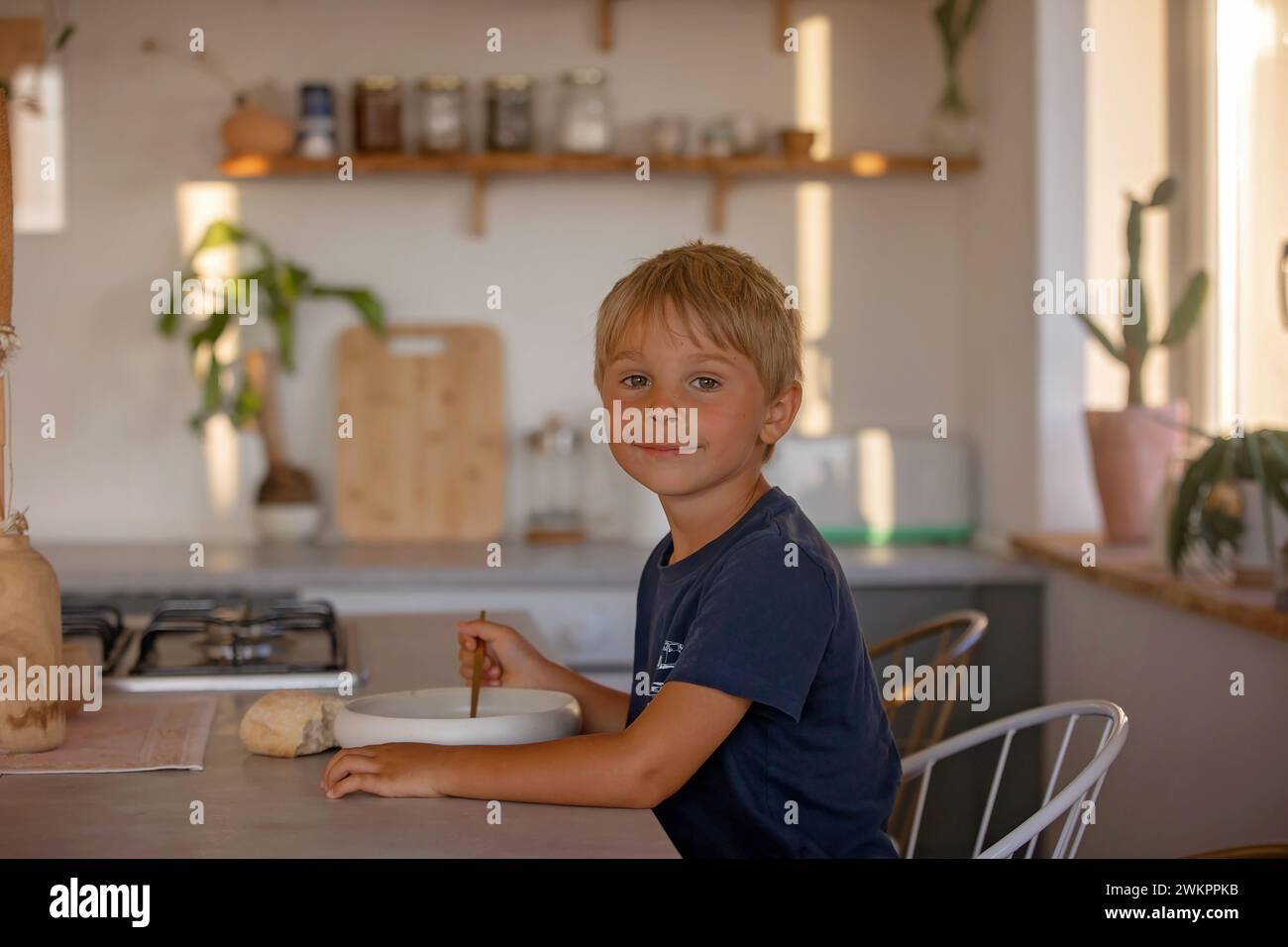 Cute blond child, boy, eating soup at home for dinner, summertime ...