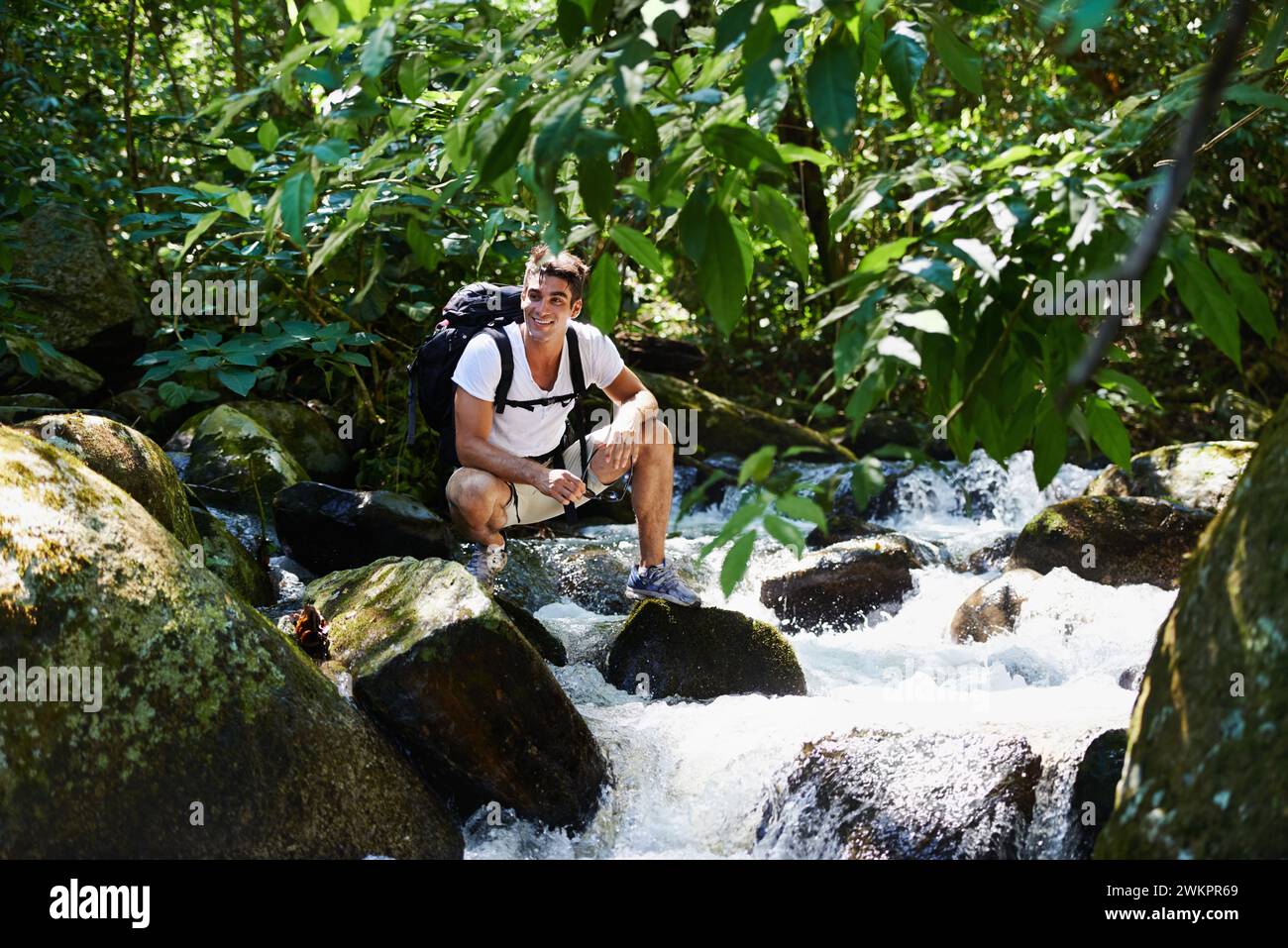 Man, hiking and river in tropical rainforest with smile for adventure ...