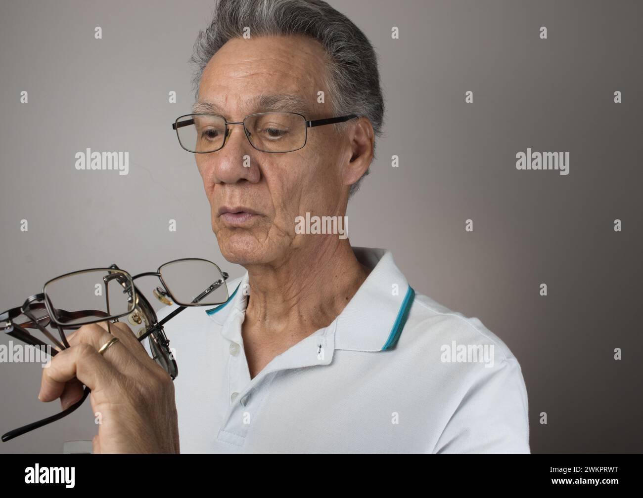 An elderly man holding up a bunch of eyeglasses Stock Photo - Alamy