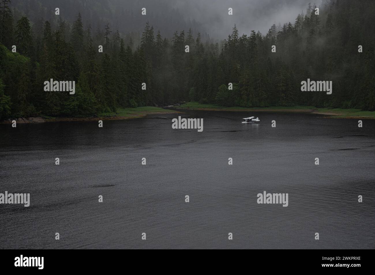 Float Plane on the water with mist and fog in the mountains around ...