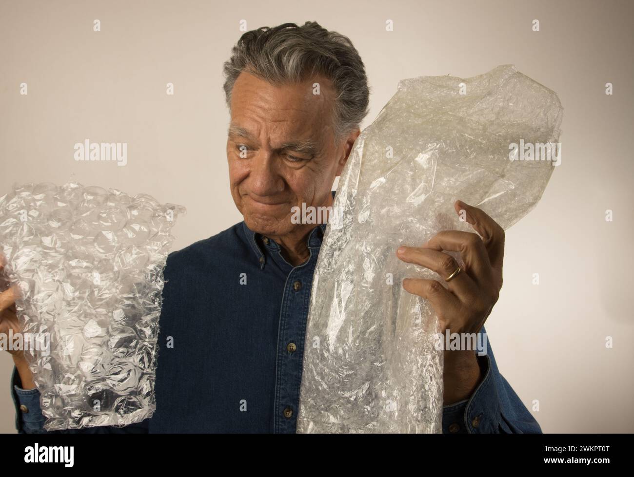An elderly man playing with bubble wrap Stock Photo - Alamy