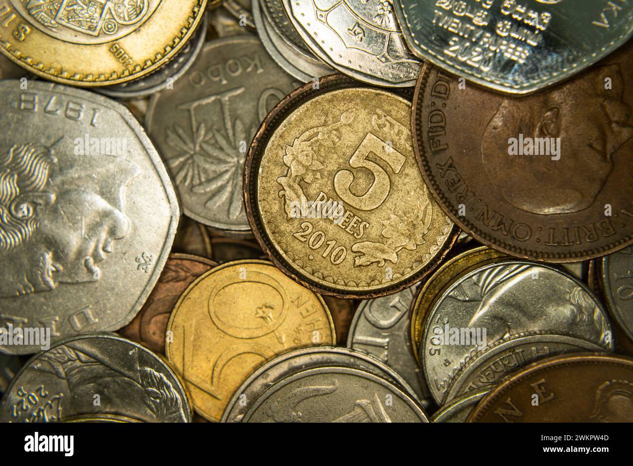 A top view of assorted coins stacked, with rupee coin at the center ...