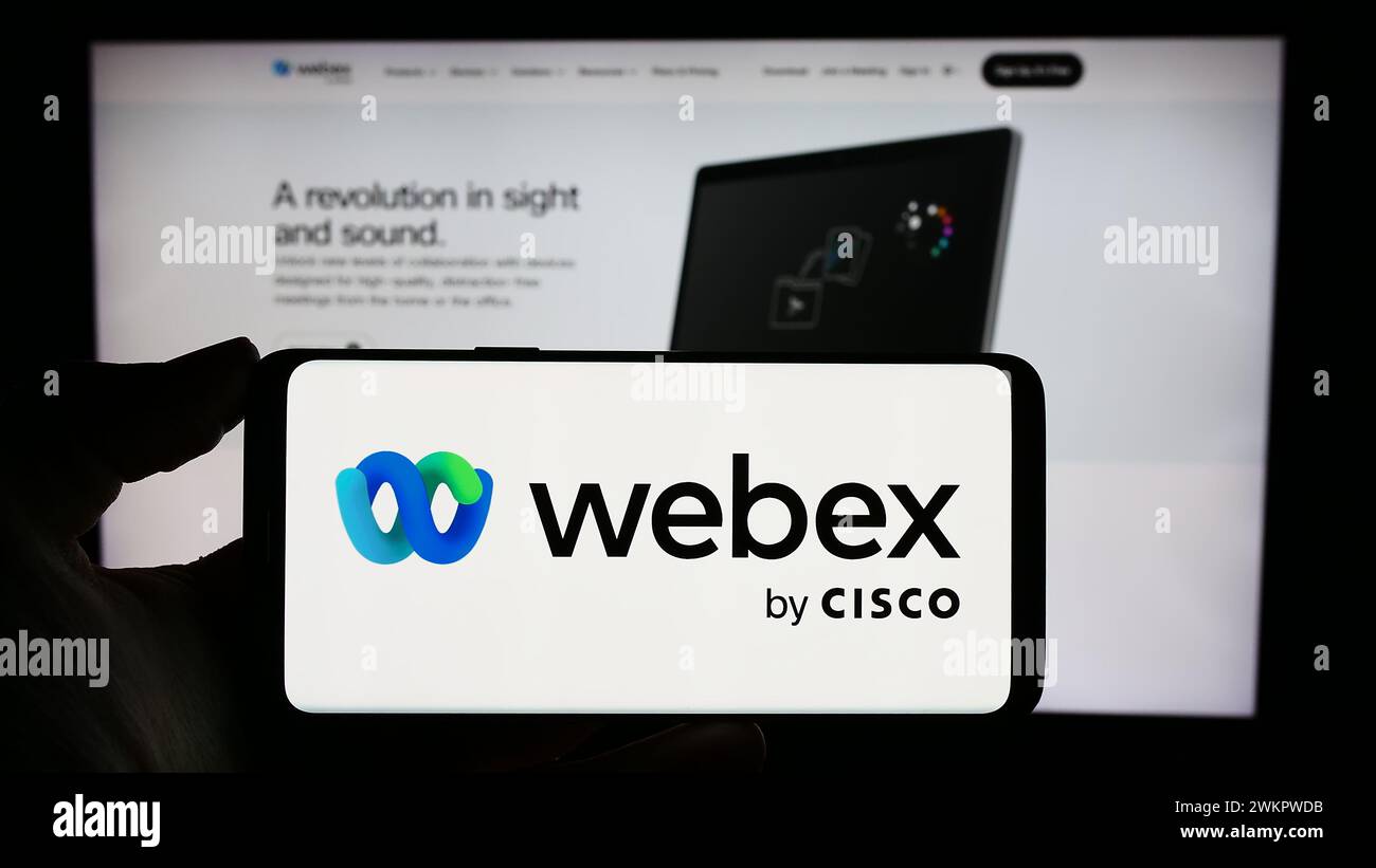 Person holding mobile phone with logo of American unified communications company Webex by Cisco ...