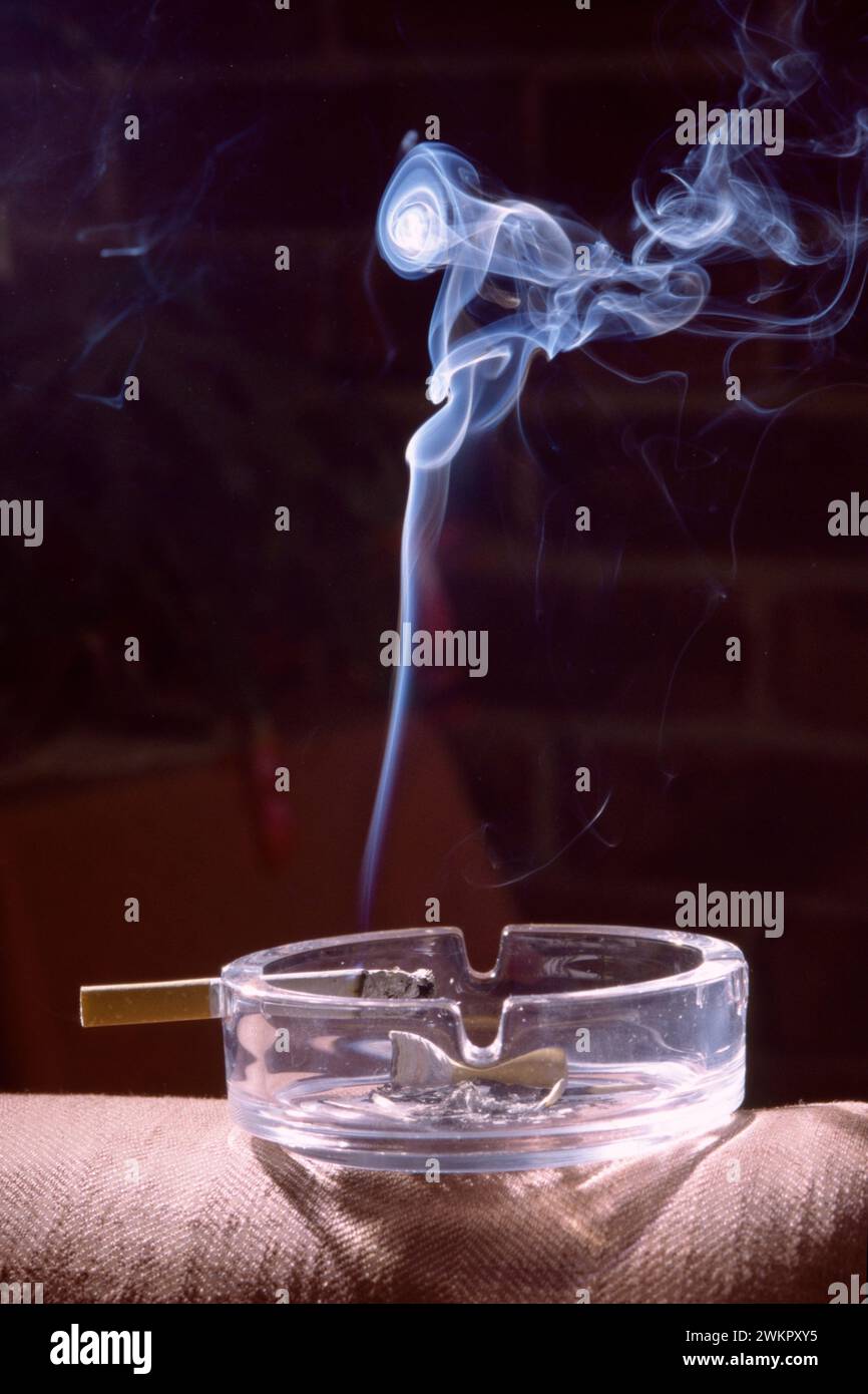 smoke from a cigarette curling up into the air from an ashtray, indoor ...