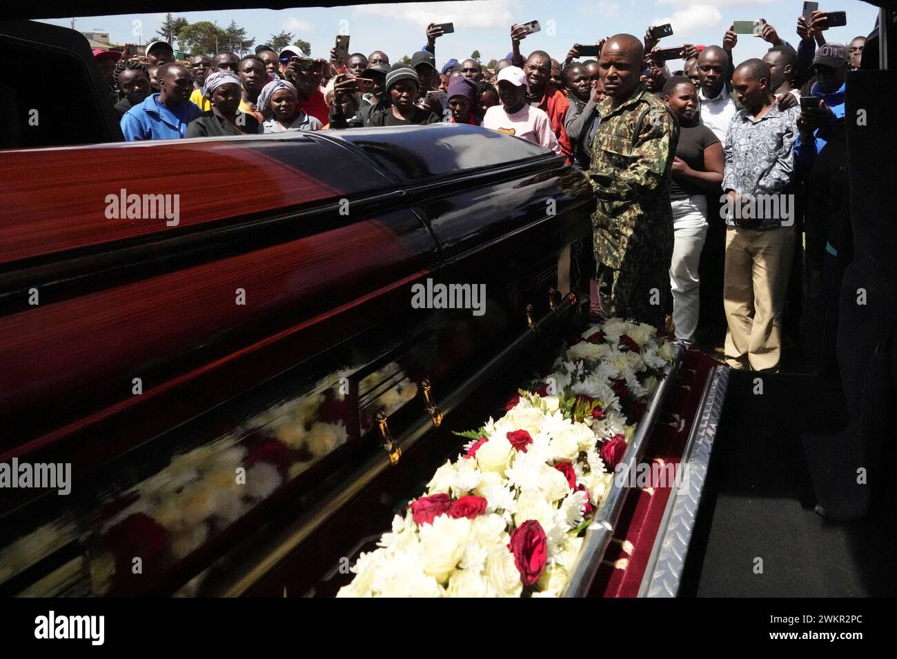 Members of the public gather around the coffin of marathon record ...