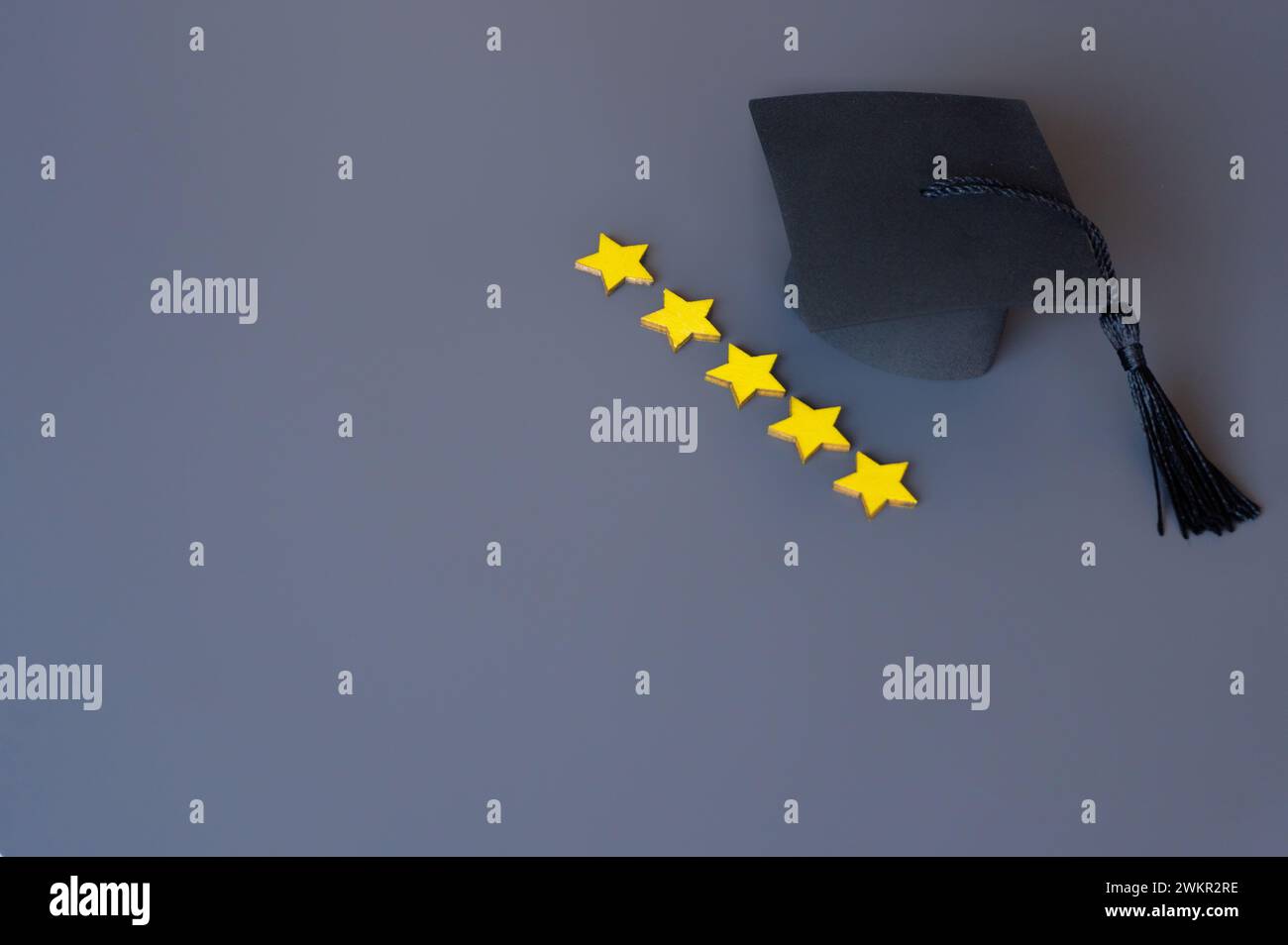 Graduation cap next to a row of five stars rating on a gray background ...