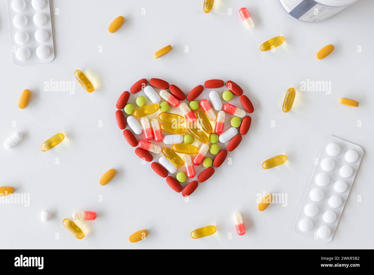 Group of pills in different colours arranged in a heart shape on a ...