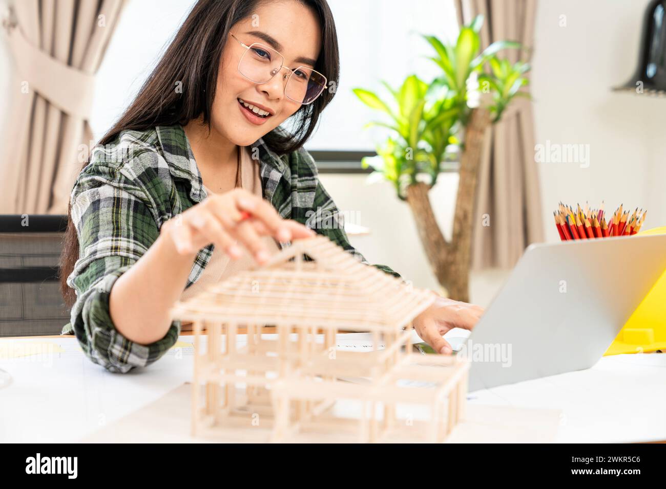 An architect is working with a model of a house in the office designing ...