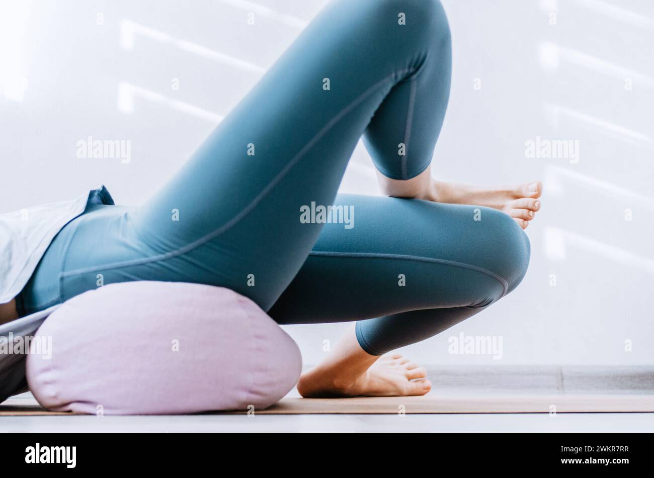 Woman doing yin yoga passive hip stretch exercises on bolster Stock ...
