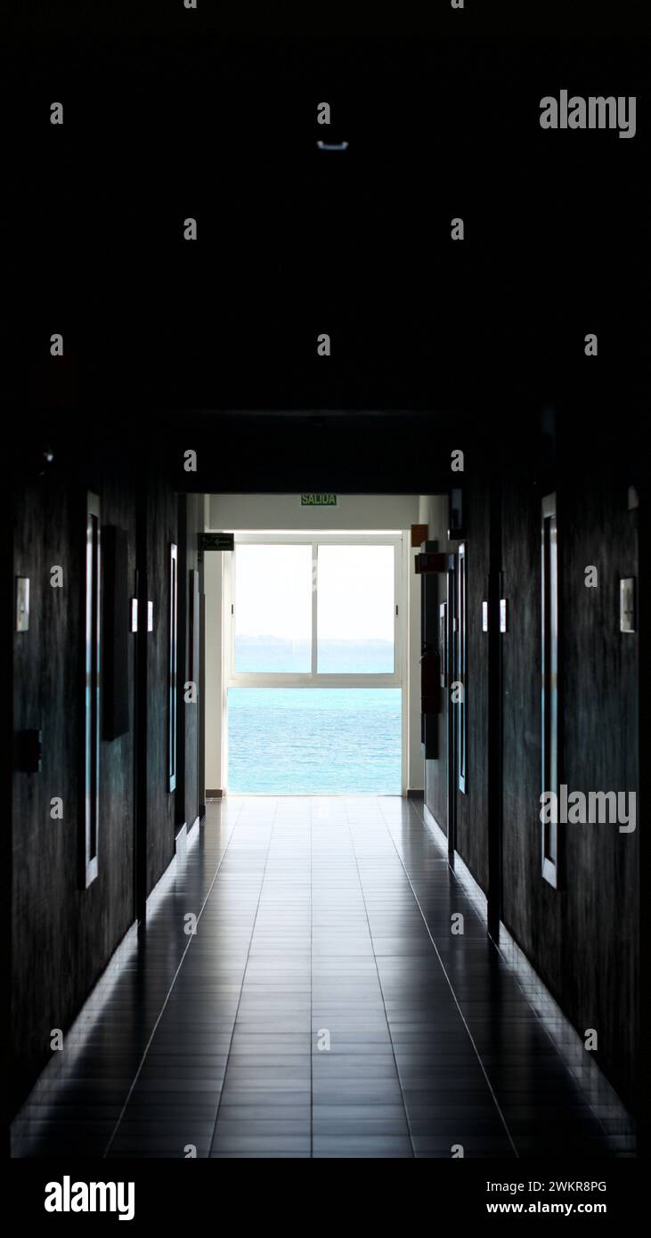 A dark hallway with tiles leading to ocean view, light illuminating the ...