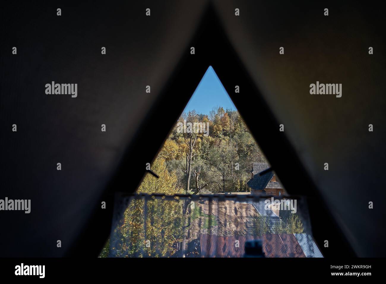 a View of the autumn forest through a triangular window in the attic ...