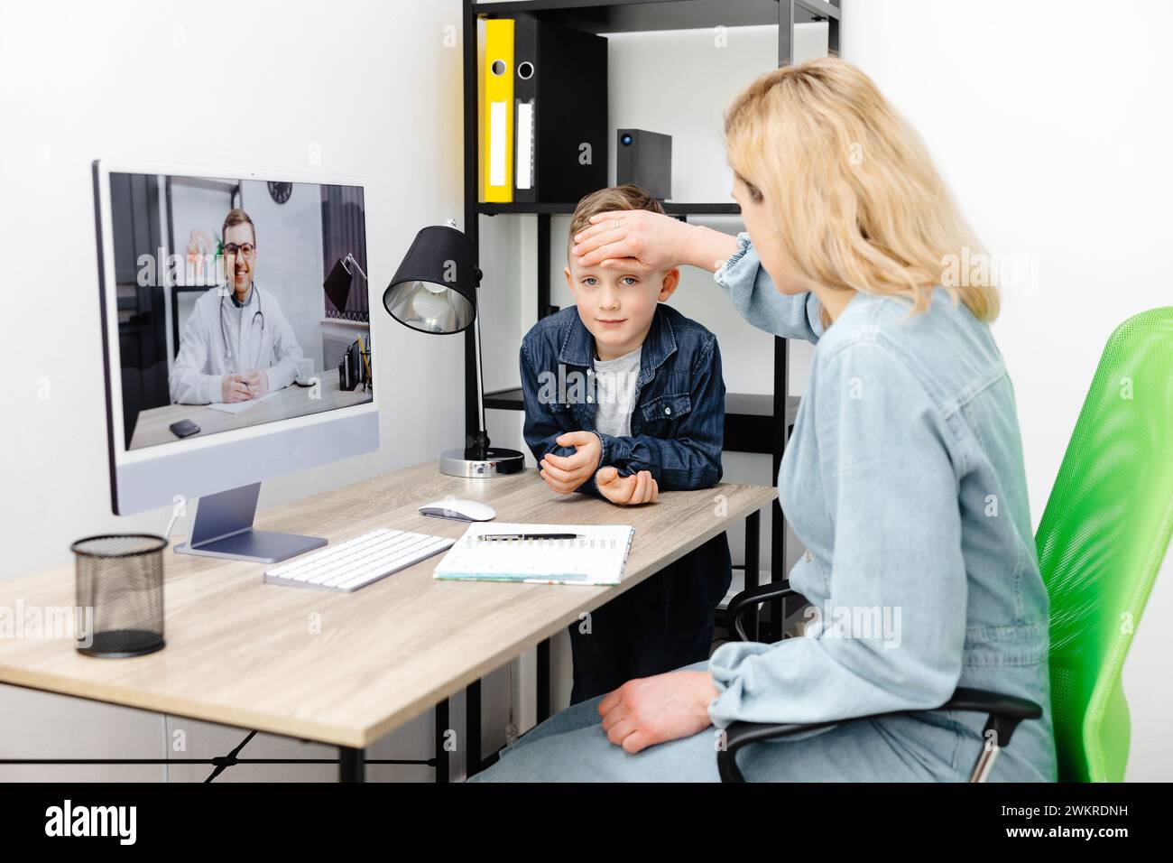 Mother checking son, touching hand on his forehead while attending ...