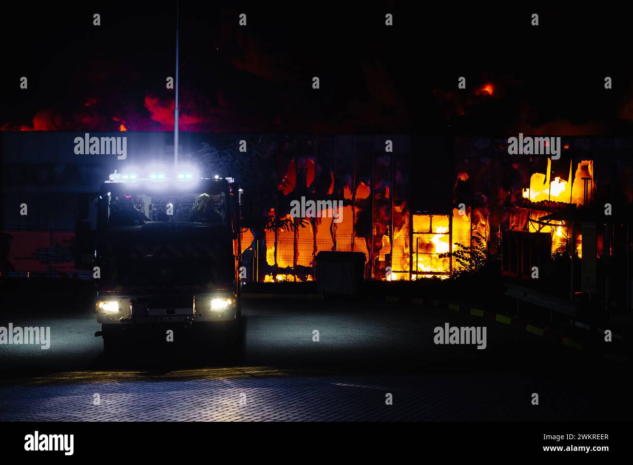 A fire truck drives down the street at night with a fire in the ...