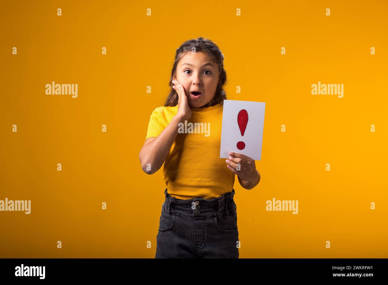 A portrait of surprised kid girl with open mouth holding exclamation ...