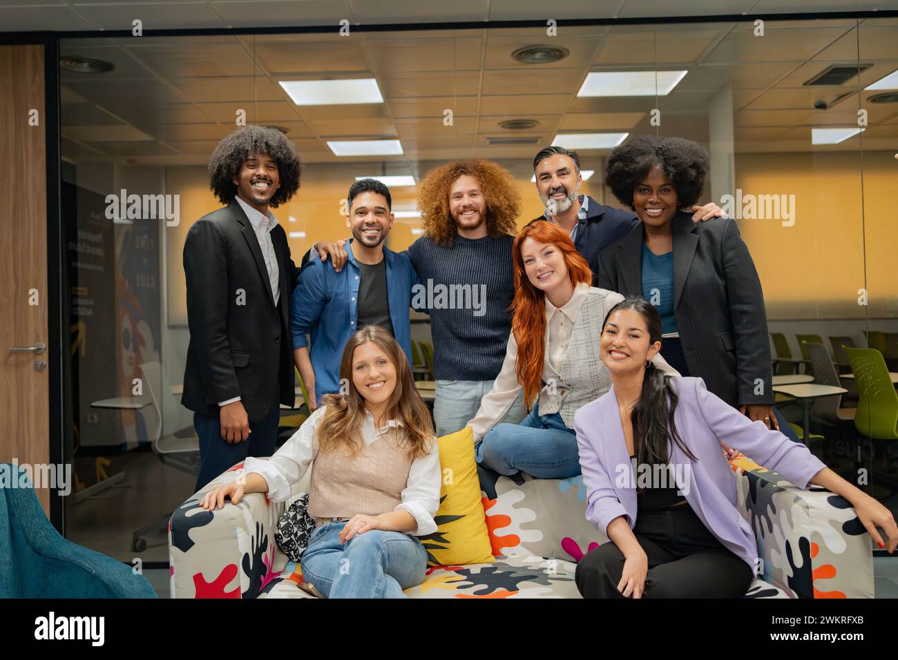 Diverse group of professionals smiling and posing together in a modern ...
