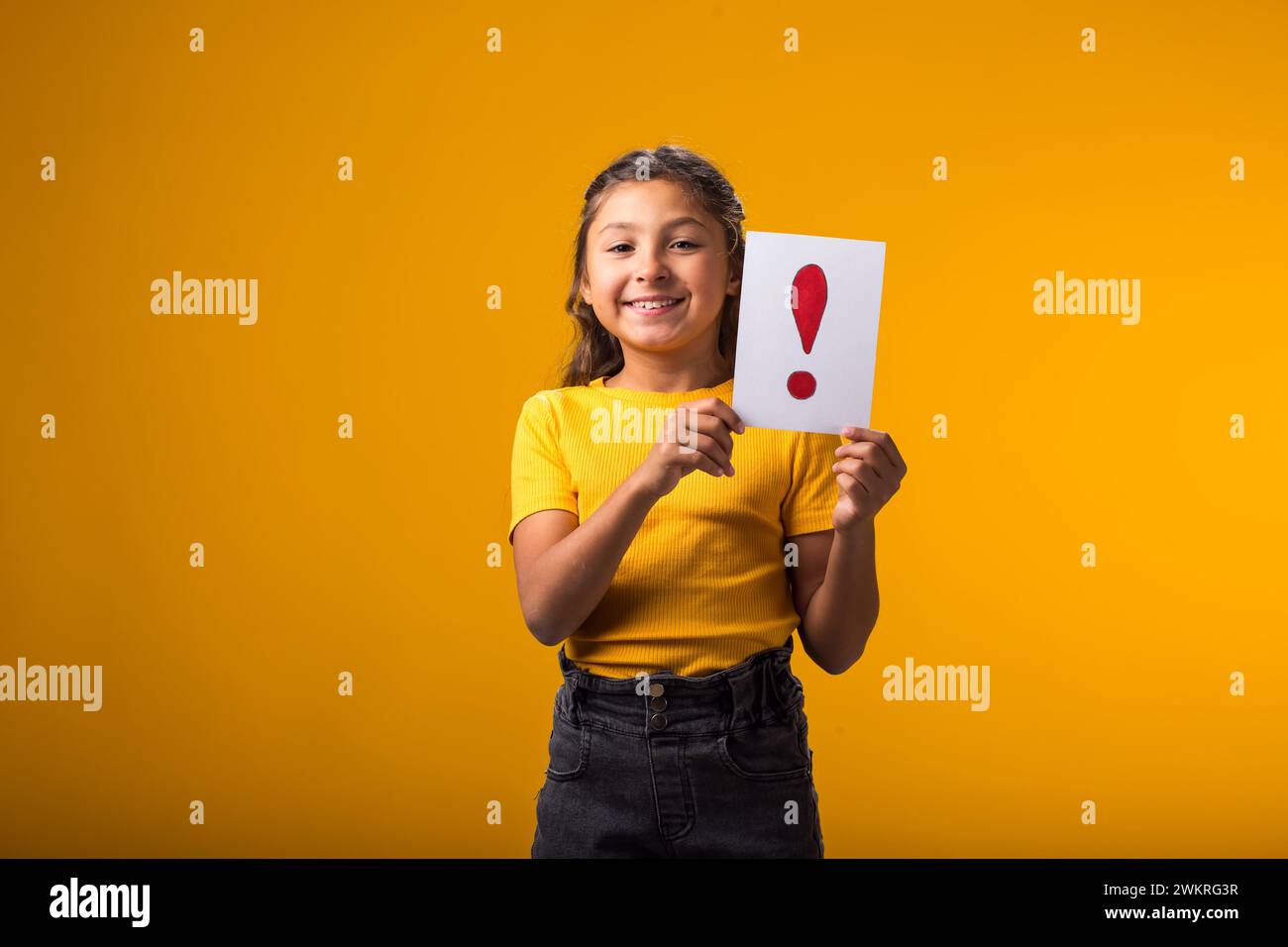 A portrait of smiling kid girl holding exclamation point card and ...