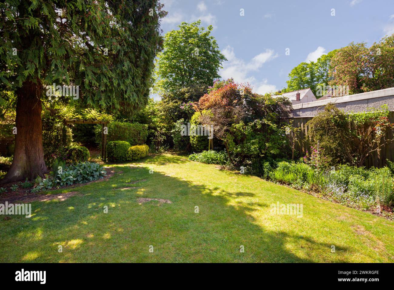Cambridge, England - May 15 2019: Mature sunlit grounds with shrubs and ...