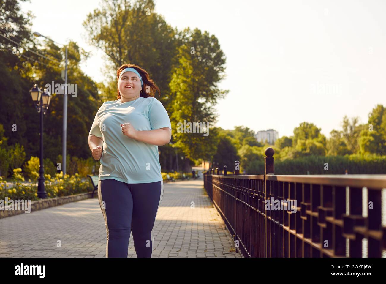 Body positive plus size woman jogging outdoors and having sport workout ...