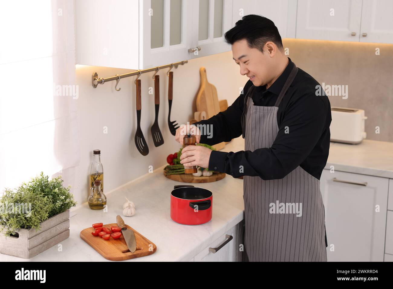 Cooking process. Man adding salt into pot at countertop in kitchen ...