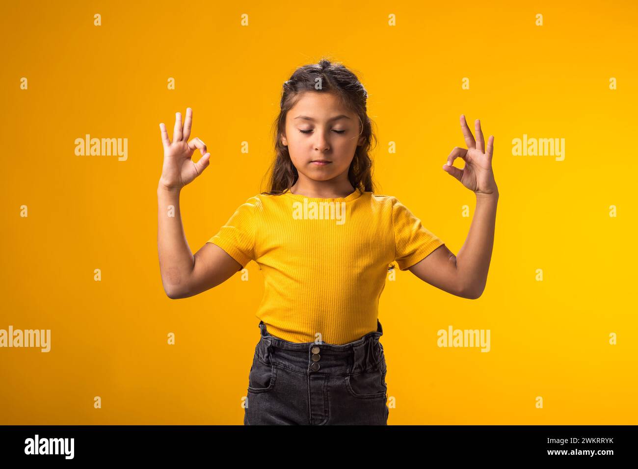 Portrait of kid girl smiling peacefully holding his fingers in mudra ...