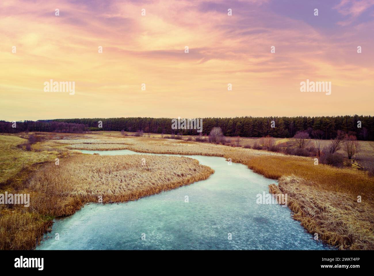 Aerial view of the countryside and frozen winding brook in the evening ...